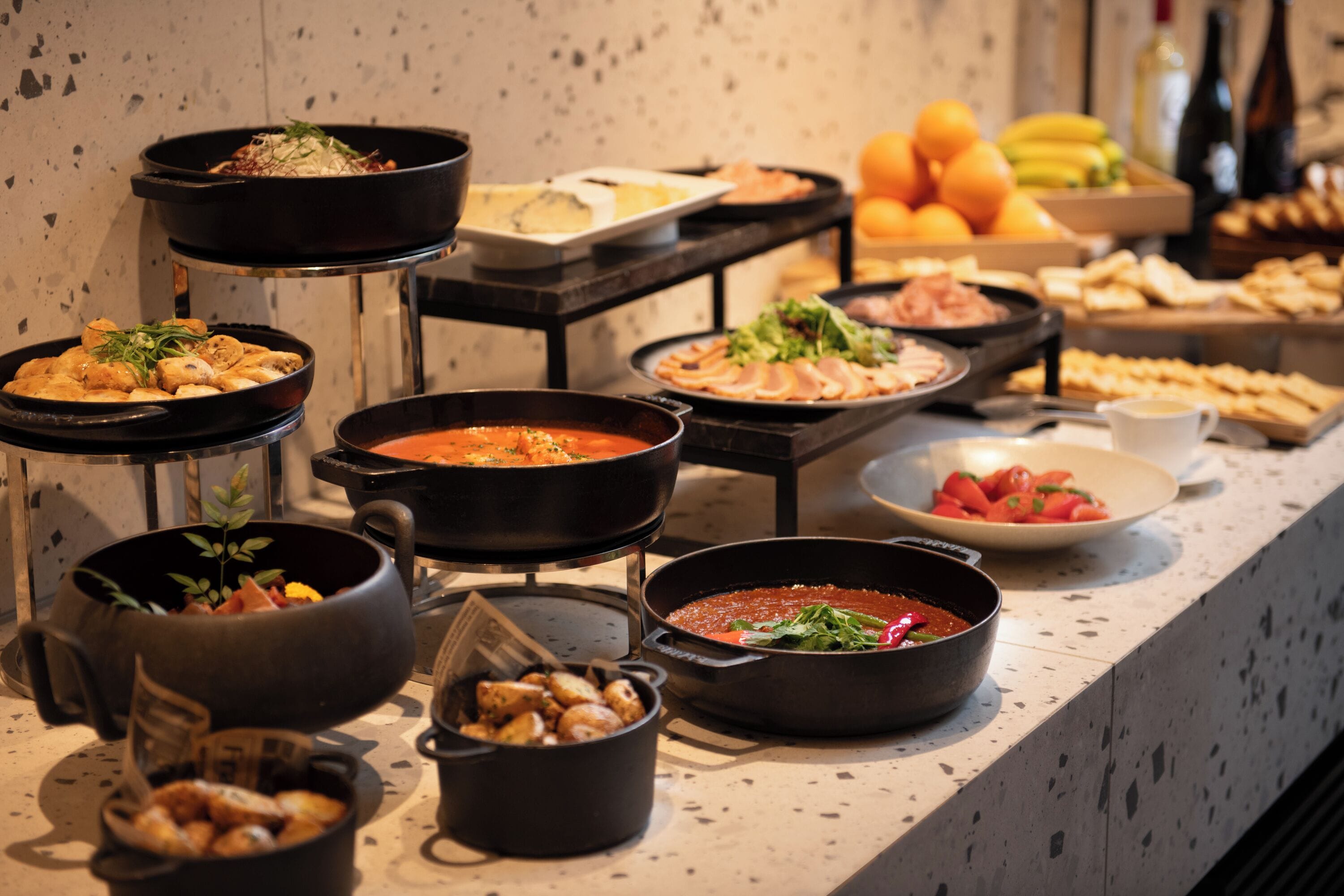 Um buffet com diversos pratos e uma exposição de frutas.