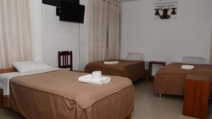 Quarto de hotel com duas camas, televisão fixada na parede e uma mesinha.