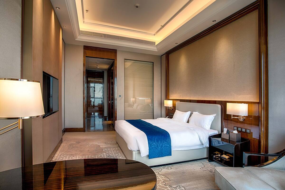 Quarto de hotel com uma cama grande, mesas de cabeceira, uma escrivaninha e uma cadeira.