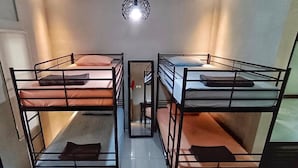 Quarto de dormitório com beliches, piso em azulejo e luminária suspensa.