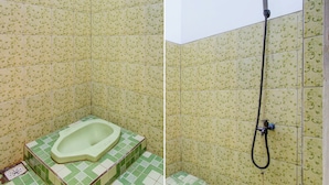 Casa de banho com sanita, chuveiro e azulejos estampados.
