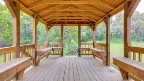 Um pavilhão de madeira com bancos e vista para uma floresta.
