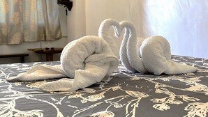 Quarto de hotel com uma cama, televisão de tela plana na parede e duas pinturas sobre a cama.