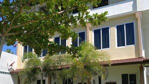 Um edifício de dois andares com varanda e um pequeno jardim.