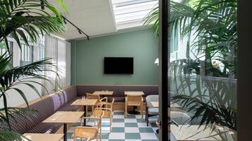 Um restaurante com piso quadriculado, paredes verdes e uma TV de tela plana fixada na parede.