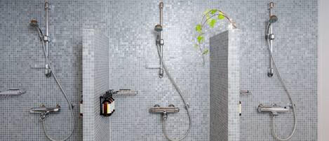 Casa de banho com três chuveiros e parede revestida a azulejos.