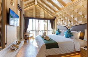 Quarto espaçoso com cama grande, televisão na parede e vista para o exterior através de amplas janelas.