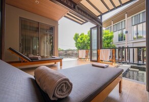 Um spa moderno com duas macas de massagem, uma pequena piscina e uma varanda com vista para a cidade.