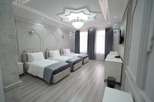Quarto de hotel moderno com duas camas, uma escrivaninha e um candelabro.