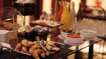 Uma mesa de buffet com diversos alimentos, incluindo croissants, tigelas de sopa e uma seleção de frutas e legumes.