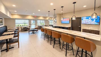 Cozinha moderna com bancada de mármore, banquetas e iluminação pendente.