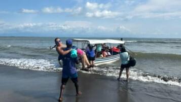 Cena de praia com um barco transportando pessoas.