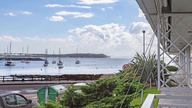 Vista costeira com barcos, um edifício verde e uma estrutura branca.