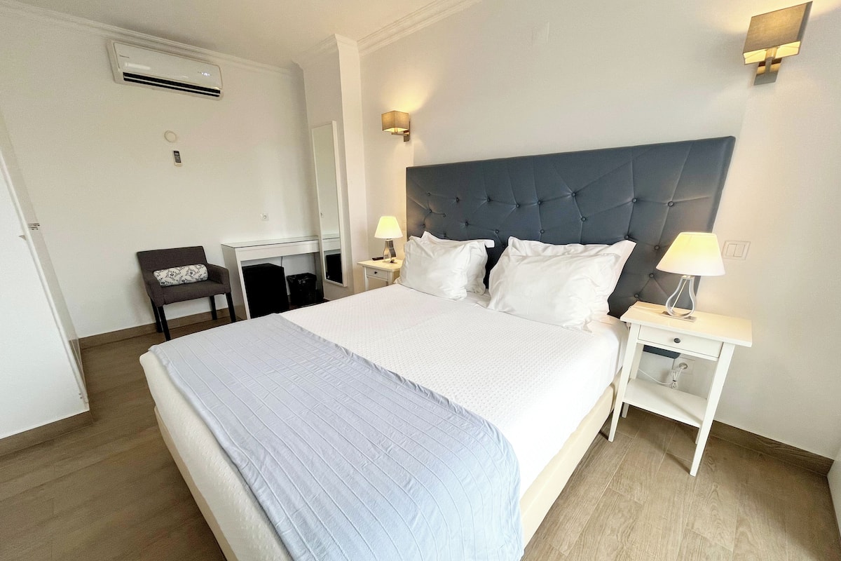 Quarto de hotel com uma cama grande, uma escrivaninha e uma cadeira.