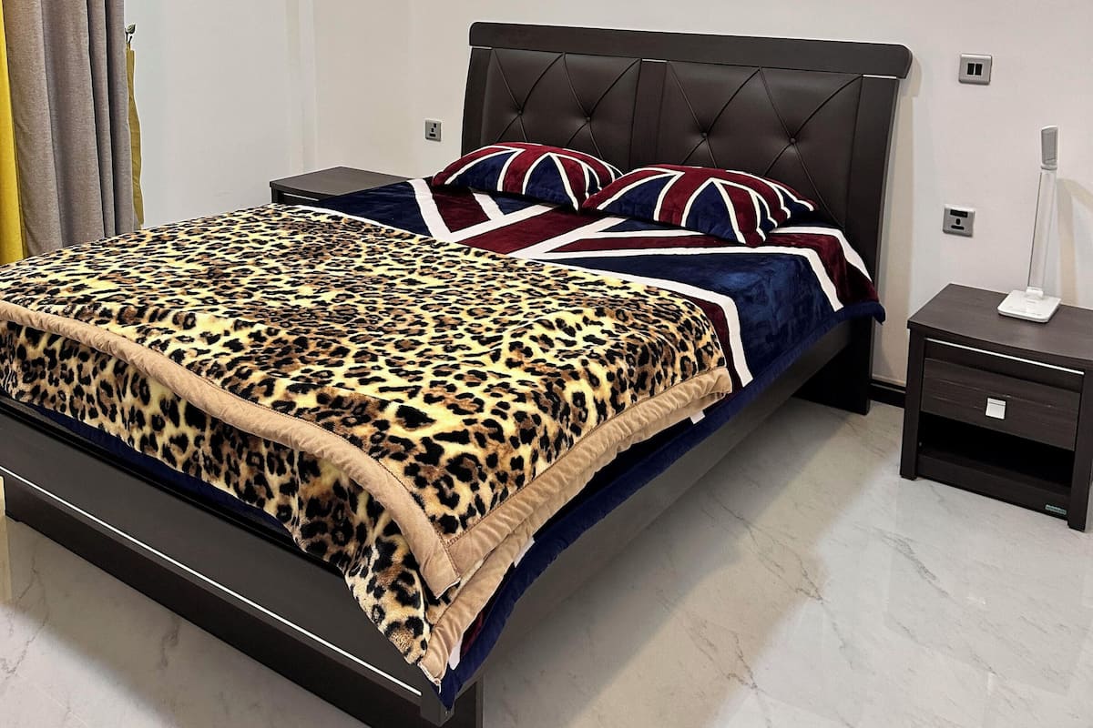 Um quarto moderno com uma cama, uma mesa de cabeceira e um abajur.