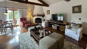 Uma sala de estar ampla, com lareira, televisão e assentos confortáveis.