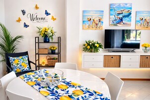 Uma área de refeições moderna com uma mesa redonda, cadeiras, uma televisão e arte decorativa na parede.