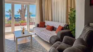 Uma sala de estar com sofá, mesa de centro e vista para a praia.