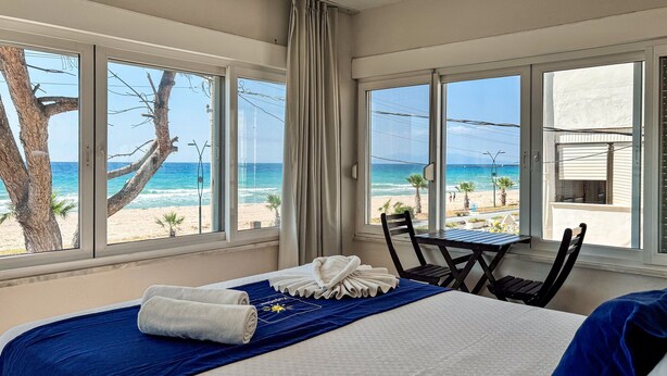 Quarto de hotel com cama, mesa e vista para a praia e oceano.