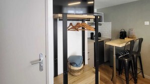 Cozinha compacta com mesa de madeira, cadeiras e um cabide.