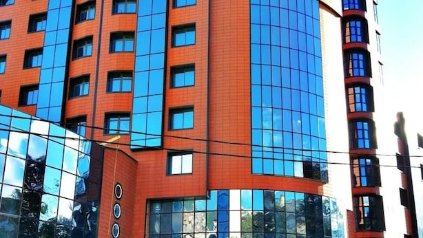 Um edifício moderno com fachada curva, grandes janelas e um logotipo 'D' em destaque.