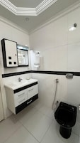 Um banheiro moderno com pia branca, toucador preto e branco, vaso sanitário preto e um espelho sobre a pia.