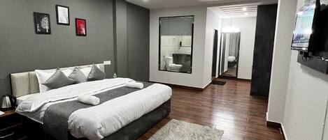 Um quarto moderno com uma cama grande, uma escrivaninha e uma televisão.