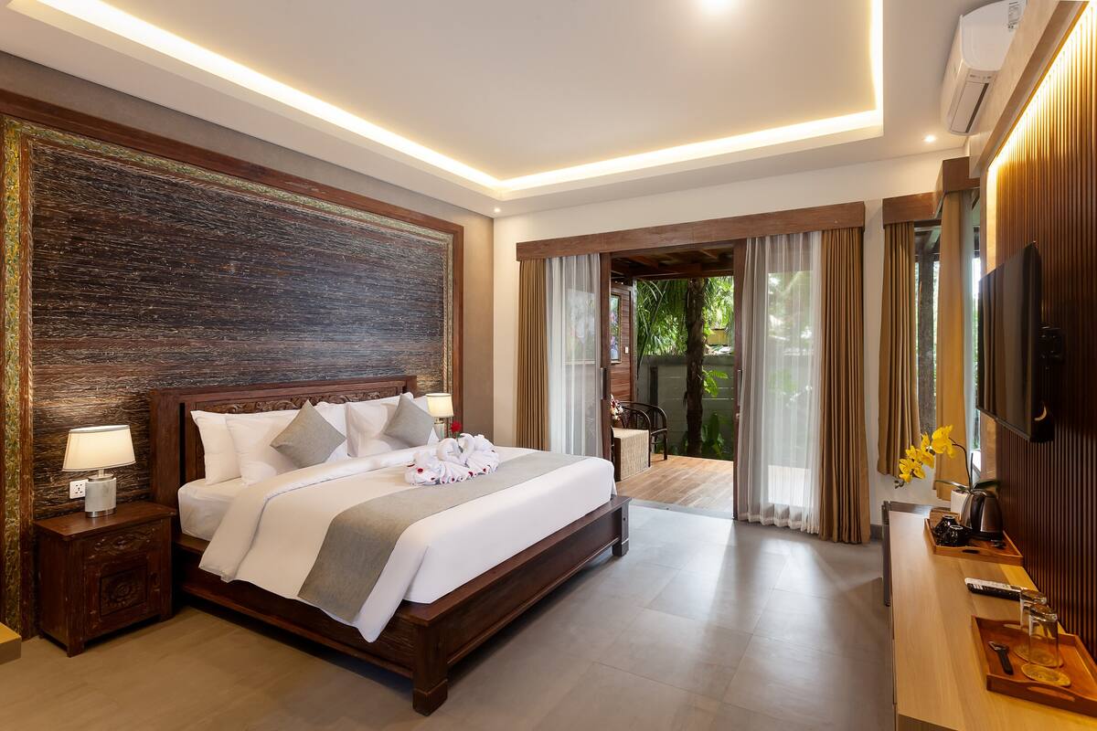 Quarto espaçoso com uma cama grande, mesas de cabeceira, uma TV e vista para o exterior.