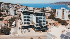 Um edifício moderno de vários andares com terraço no telhado, situado perto da costa e com vista para o mar.