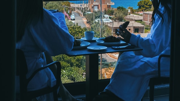 Duas pessoas sentadas à mesa com vista para o mar e uma ilha ao longe.
