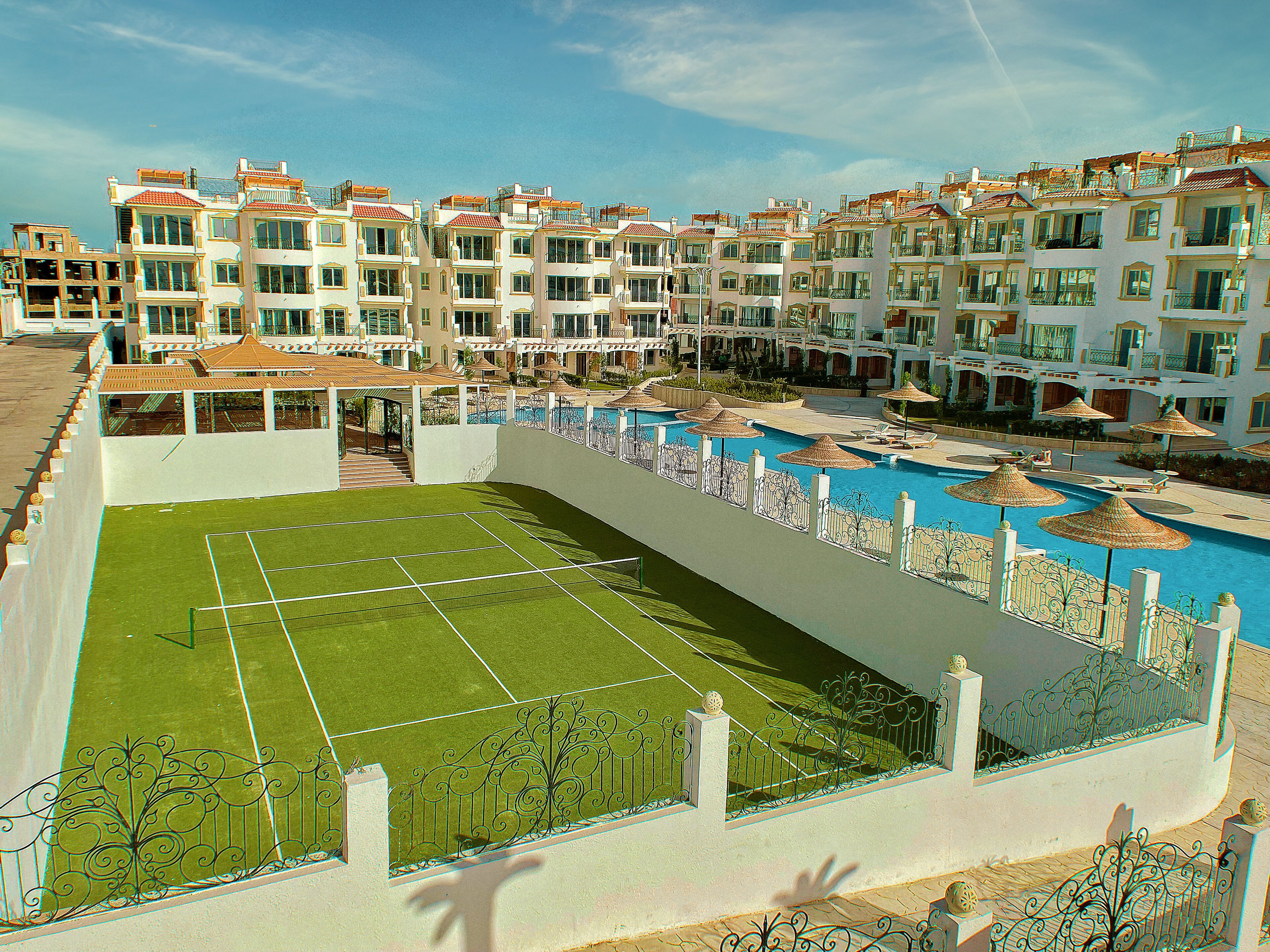 Hotel com várias varandas, piscina e quadra de tênis.