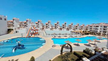Um resort com várias piscinas, um tobogã e vista para o mar.