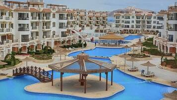 Um resort com várias piscinas, um gazebo e uma ponte que as conecta.