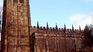 Um edifício histórico com uma torre alta e várias janelas em arco.