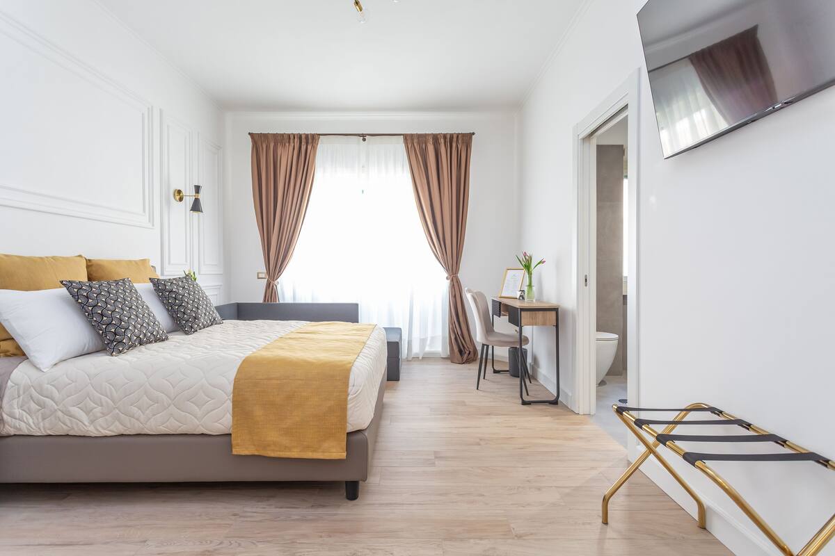 Quarto moderno com cama, escrivaninha e televisão.
