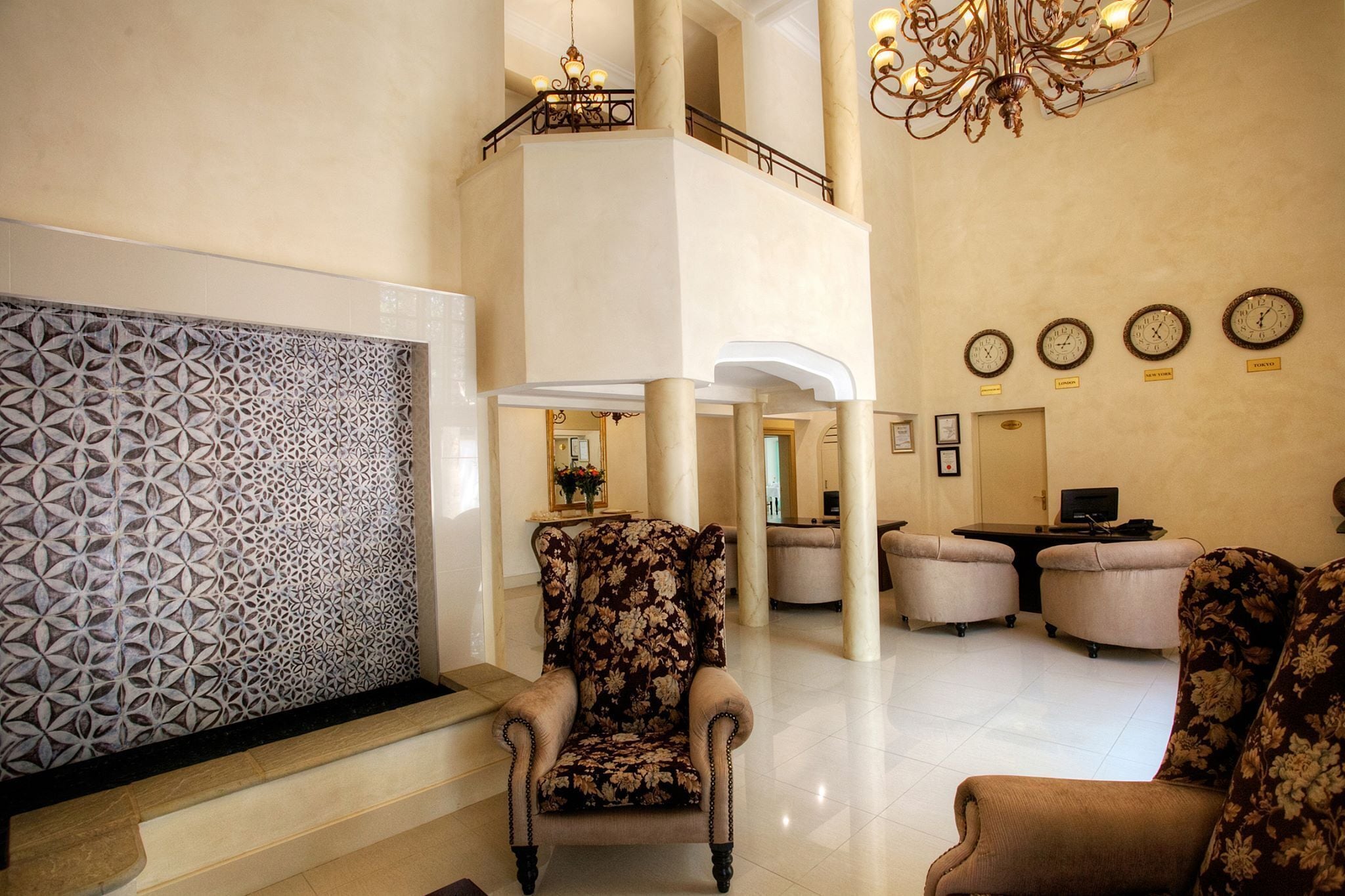 Um hall amplo com teto alto, uma parede decorativa e um espaço de estar com poltronas.