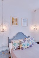 Quarto com cama, duas luminárias de parede e duas obras de arte emolduradas.