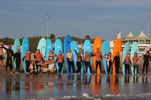 Um grupo de pessoas carregando pranchas de surf na praia.