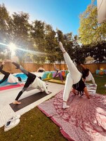 Um grupo de pessoas praticando yoga ao ar livre em tapetes e cobertores.