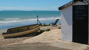 Uma cabana à beira-mar com a placa 'FISHERMAN'S Hut', indicando que está aberta das 11h30 às 13h.