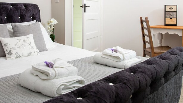 Quarto de hotel com cama, escrivaninha e cadeira.