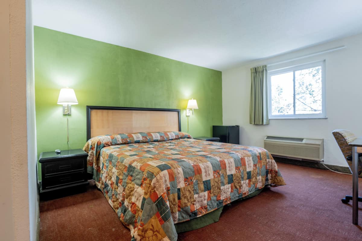 Quarto com cama, duas luminárias de cabeceira, escrivaninha e uma cadeira.