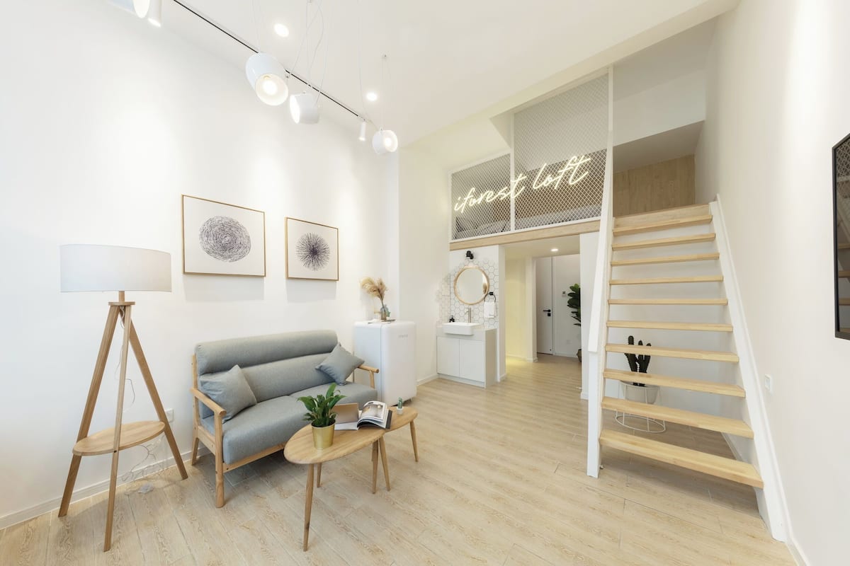Uma sala de estar moderna com sofá, mesa de centro, luminária de chão e obras de arte na parede.