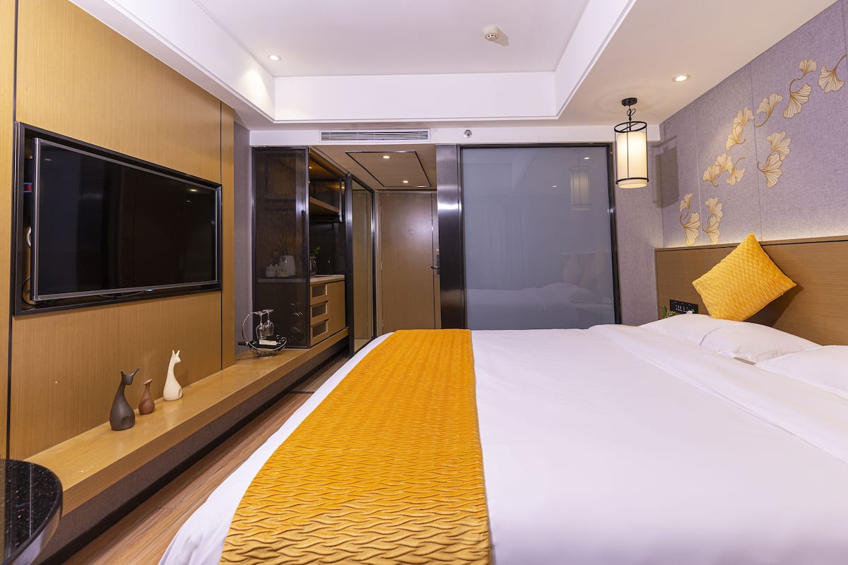 Quarto de hotel com cama, televisão, guarda-roupa e banheiro.