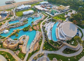 Vista aérea de um resort com várias piscinas, um edifício circular grande e um parque aquático.