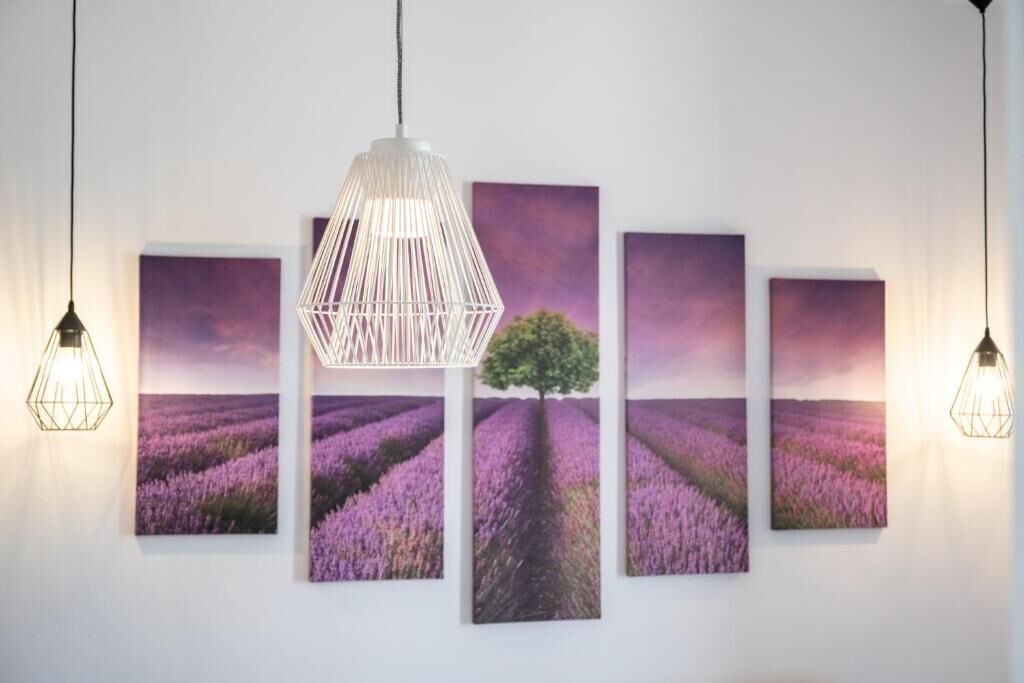 Paredes com cinco quadros de campos de lavanda e duas luminárias pendentes.