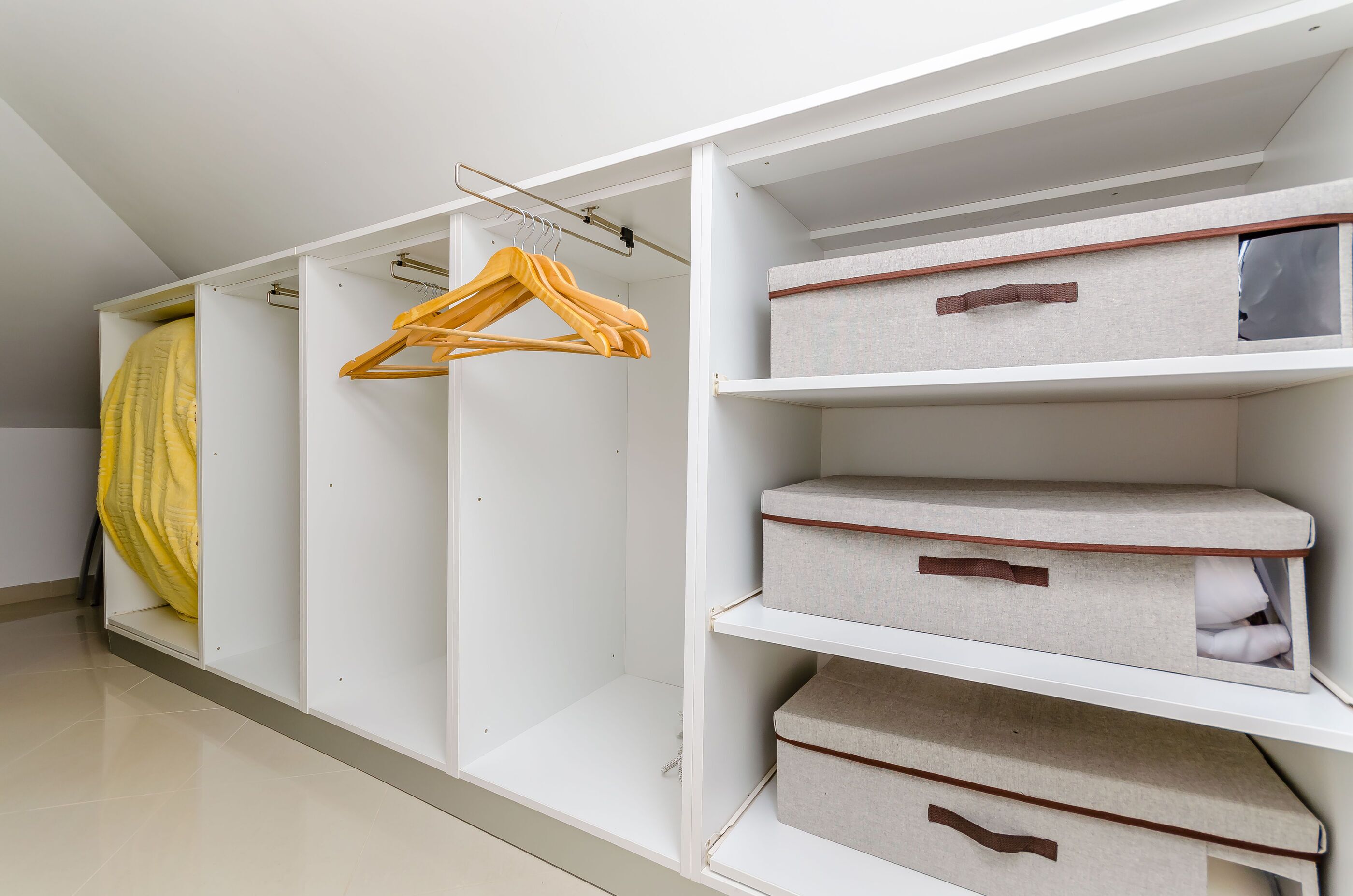 Um closet espaçoso com prateleiras abertas, barra para pendurar roupas e caixas organizadoras.