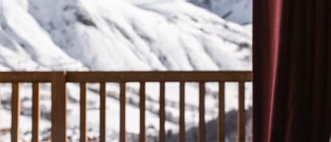 Cama com vista para montanhas cobertas de neve através de uma varanda.