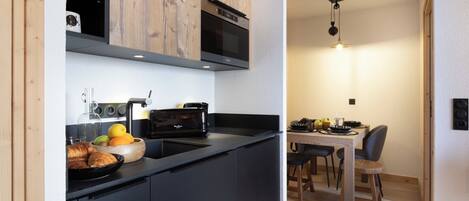Cozinha compacta com bancada preta, torradeira e armário de madeira sobre o micro-ondas.
