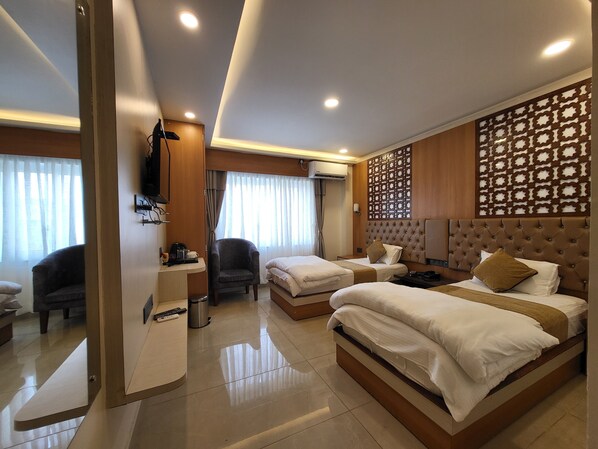 Quarto de hotel com duas camas, uma escrivaninha, uma cadeira e um painel decorativo na parede.